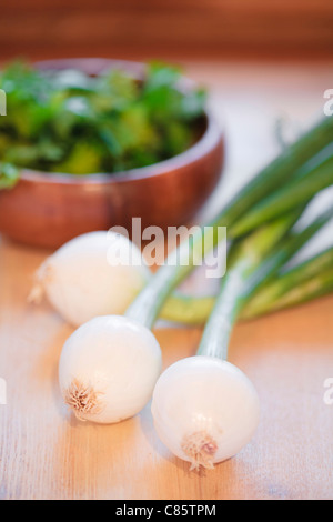 Closeup of whole green onions scallions on old rustic chopping board ...