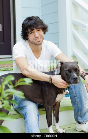 Young hispanic man hugging dog celebrate new year sitting by christmas ...