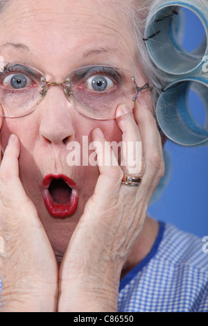 Shocked middle-aged woman with curly hair in blue shirt points with an ...