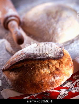 A loaf of bread with a rolling pin for dough stand on a craft linen bag ...