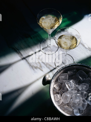 Bucket of champagne and glasses on a marble counter in a warmly lit ...