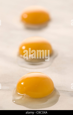 Three raw egg yolks in rustic clay bowl on white surface Stock Photo ...