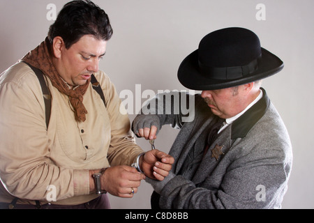 A old west sheriff putting handcuffs on a cowboy Stock Photo - Alamy