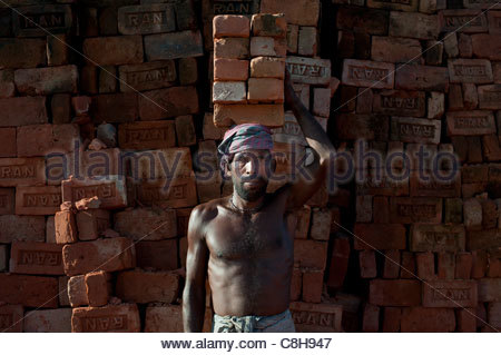 A labor carrying bricks to load on a truck at a brick factory on the ...
