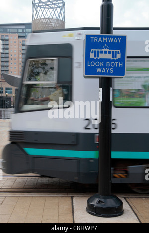 Manchester Metrolink tram moving past a "Look Both Ways" tram sign ...