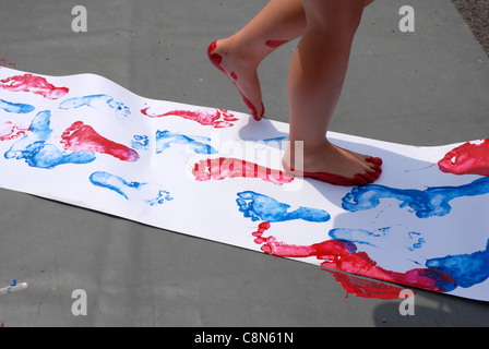 Nursery child painting footprints by walking in paint with bare feet ...