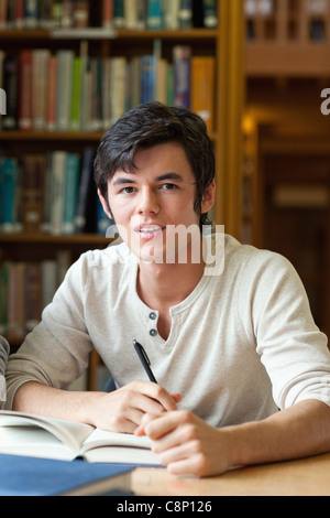 University student reviewing her notes sitting on a park bench ...