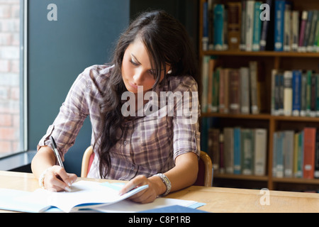 Pretty, young college student writing on the chalkboard/blackboard ...