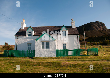 White Scottish Highland croft cottage with blue door and grazing sheep ...