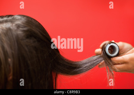 Close-up of female hands rolling dough with pin on wooden table ...
