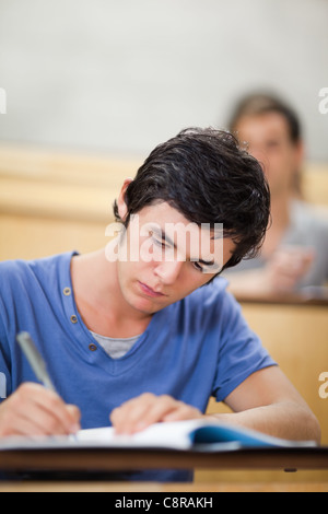 Young student with pencil making notes during online lesson with ...