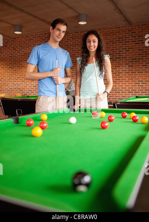 Beautiful female billiard player holding beer mug next to pool table ...