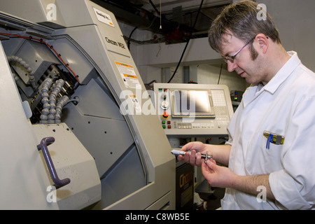 CNC lathe operator checking accuracy of a job with a micrometer Stock ...