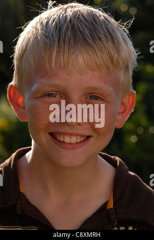 Portrait smiling blond boy bright blue eyes stands among crowd outdoor ...