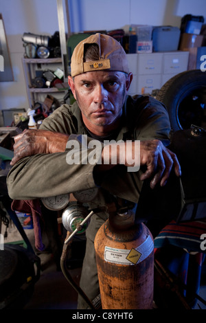 A grease covered blue collar working man takes a break, looking ...