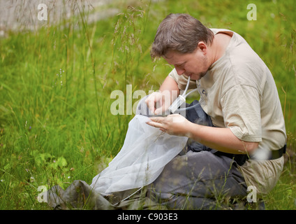 Scientist entomologist with net and aspirator collecting insect in ...