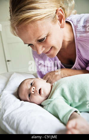 Mother and daughter admiring baby on living room floor Stock Photo - Alamy