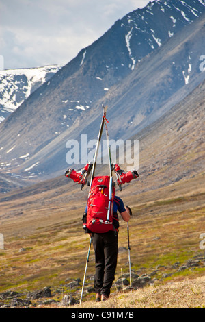 Backpacker carrying skis up Katak Creek valley on the approach to the ...