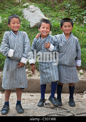 Bhutanese boys in traditional dress the gho, a knee-length robe tied ...