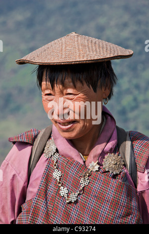 A Bhutanese woman in national dress wears a traditional bamboo hat ...