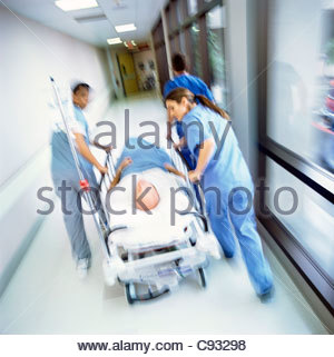 Doctors and nurse rushing patient in stretcher in hospital corridor ...
