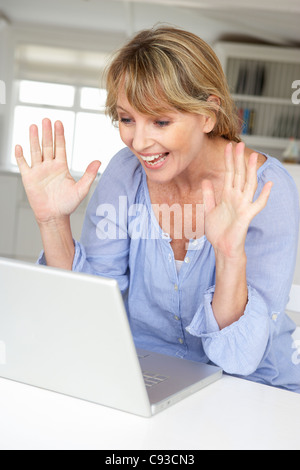 Smiling mid adult woman using smartphone while sitting on wooden pier ...