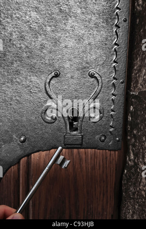 Hand placing a key into keyhole of door Stock Photo - Alamy