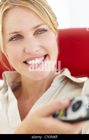 Blonde woman changing tv channel using television remote control over ...