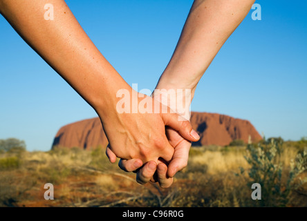 Couple holding hands with Uluru (Ayers Rock) in background. Uluru-Kata ...