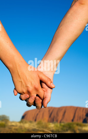 Couple holding hands with Uluru (Ayers Rock) in background. Uluru-Kata ...