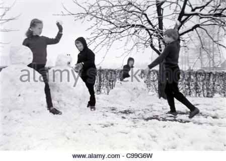1960s, young children in winter clothing playing together outside in ...
