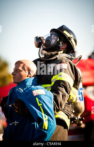 A firefighter drags a firehose while wearing full firefighting gear and ...
