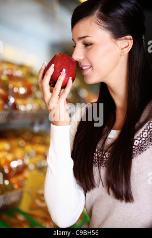 Female customer in supermarket smelling mango. Woman chooses fruit in ...