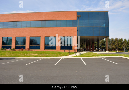 Modern red brick building with parking area for cars at side of road ...