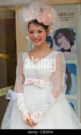 bride in white wedding dress touching nose while holding smelly flowers ...