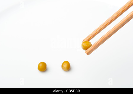 Three green peas and a pair of chop sticks Stock Photo - Alamy