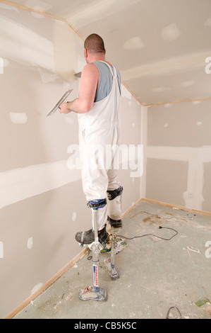 Man plastering wall on stilts Stock Photo - Alamy