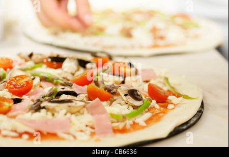 Preparing a pizza putting various ingredients over the dough before ...