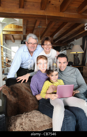 Family gathered around laptop computer, father and son smiling at ...