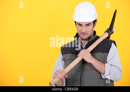 craftsman holding pickaxe against yellow background Stock Photo - Alamy