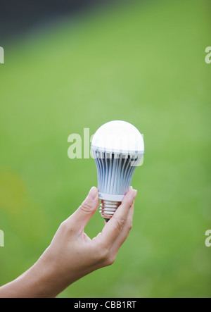 woman's hand holding led light bulb on black background, energy concept ...