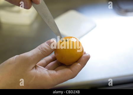 cropped image of man cutting oranges by knife on tabletop Stock Photo ...