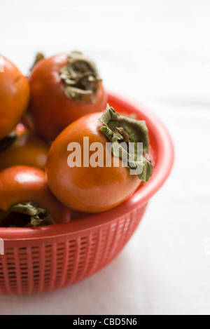 Ripe persimmons in colander Stock Photo - Alamy