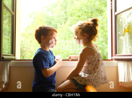 A brother and sister talking to each other by a window Stock Photo - Alamy