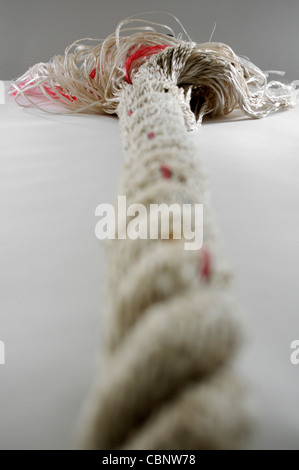 Neatly twisted multi-ply rope coming apart into a disorganized tangle ...