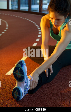 Getting ready for her run. Young woman tying her shoelaces while ...