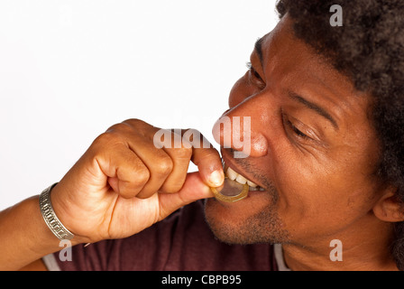 Guy biting in a coin to find out if it is real Stock Photo - Alamy