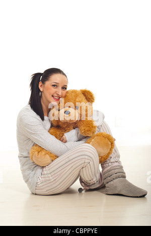 Young woman wearing pyjama hugging pillow smiling amazed and surprised ...