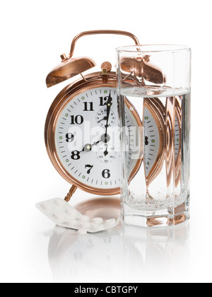 Clock with pills and glass of water on table in room, closeup Stock ...