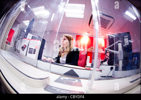 a woman bank teller working behind the counter at a branch of HSBC high ...